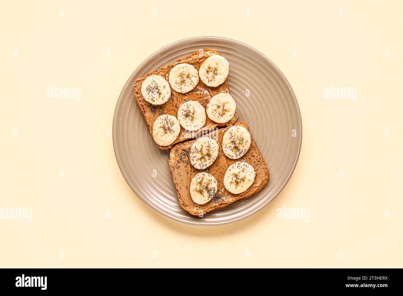 Plate of toasts with peanut butter, banana and poppy seeds on yellow ...
