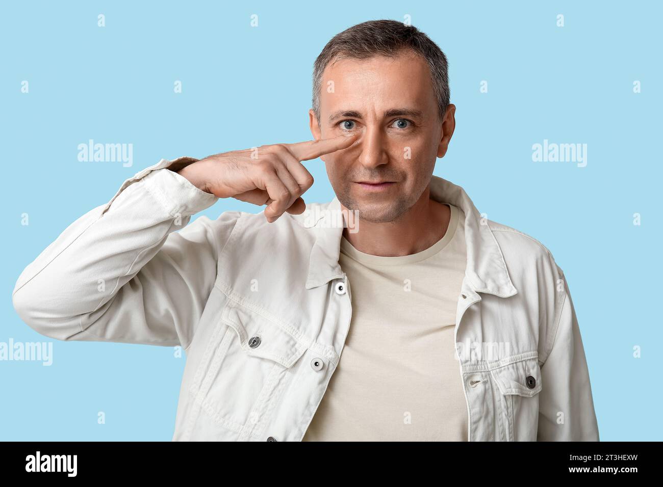 Ill mature man pointing at nose on blue background Stock Photo - Alamy