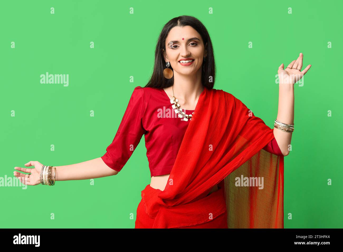 Beautiful young Indian woman in sari dancing on green background ...