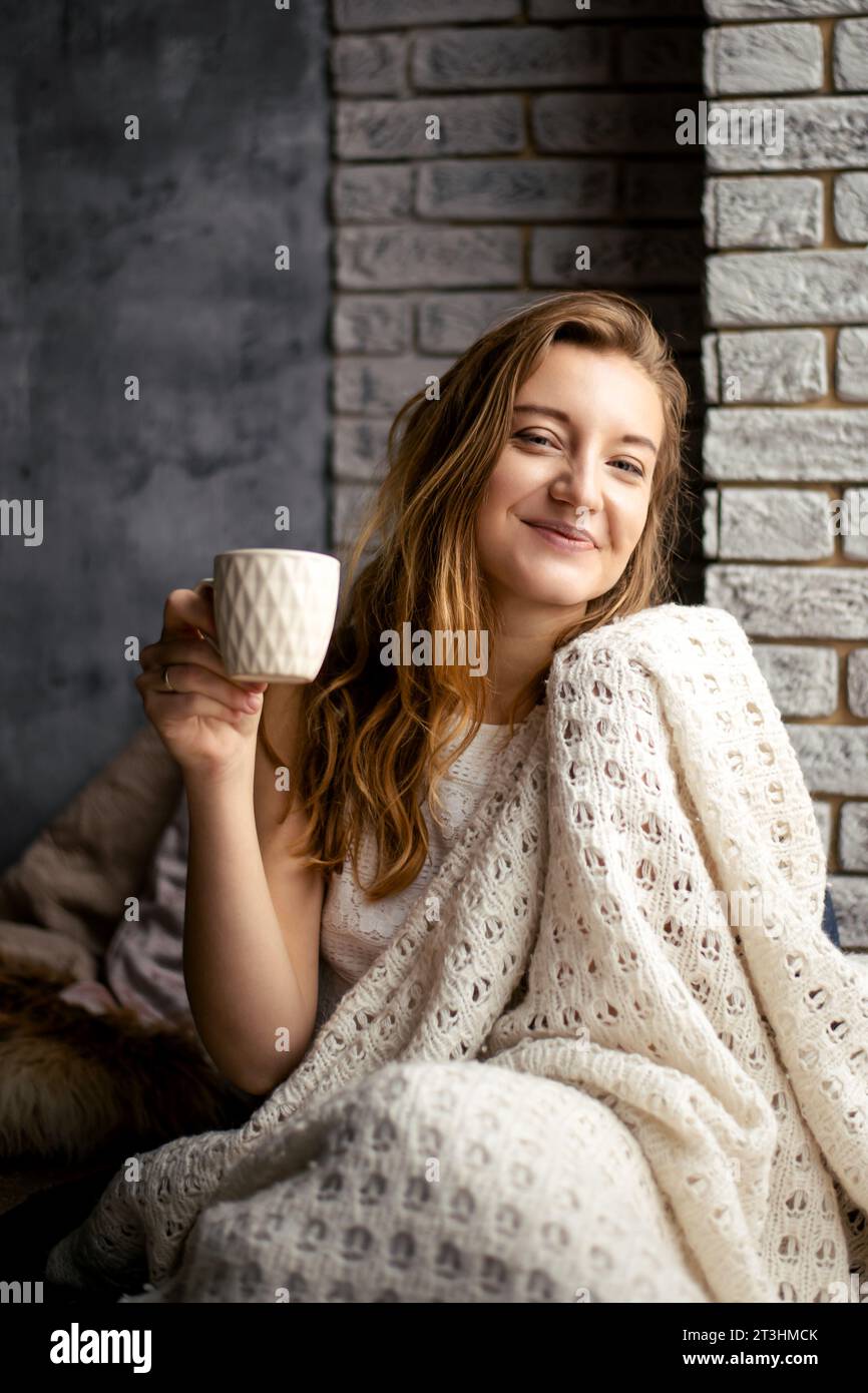 A cheerful young lady holds a coffee cup, her smile mirroring the ...