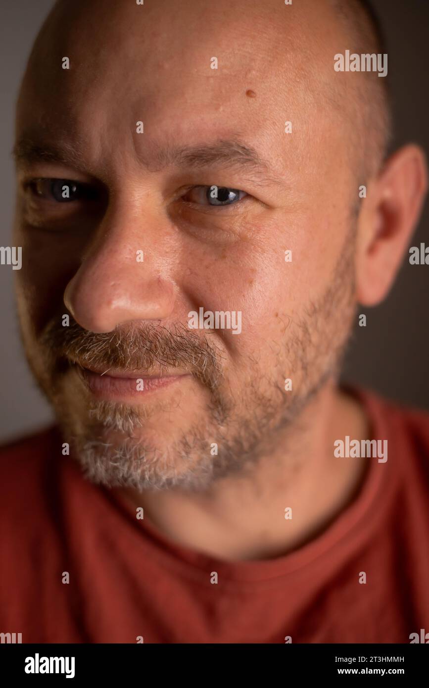 In this close-up shot, a middle-aged man in his 40s, unshaven and ...