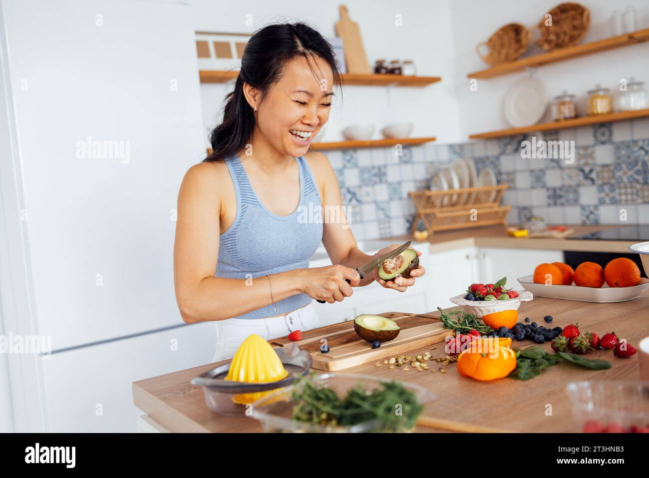 An attractive cute Asian woman smiles and cooks breakfast in the ...