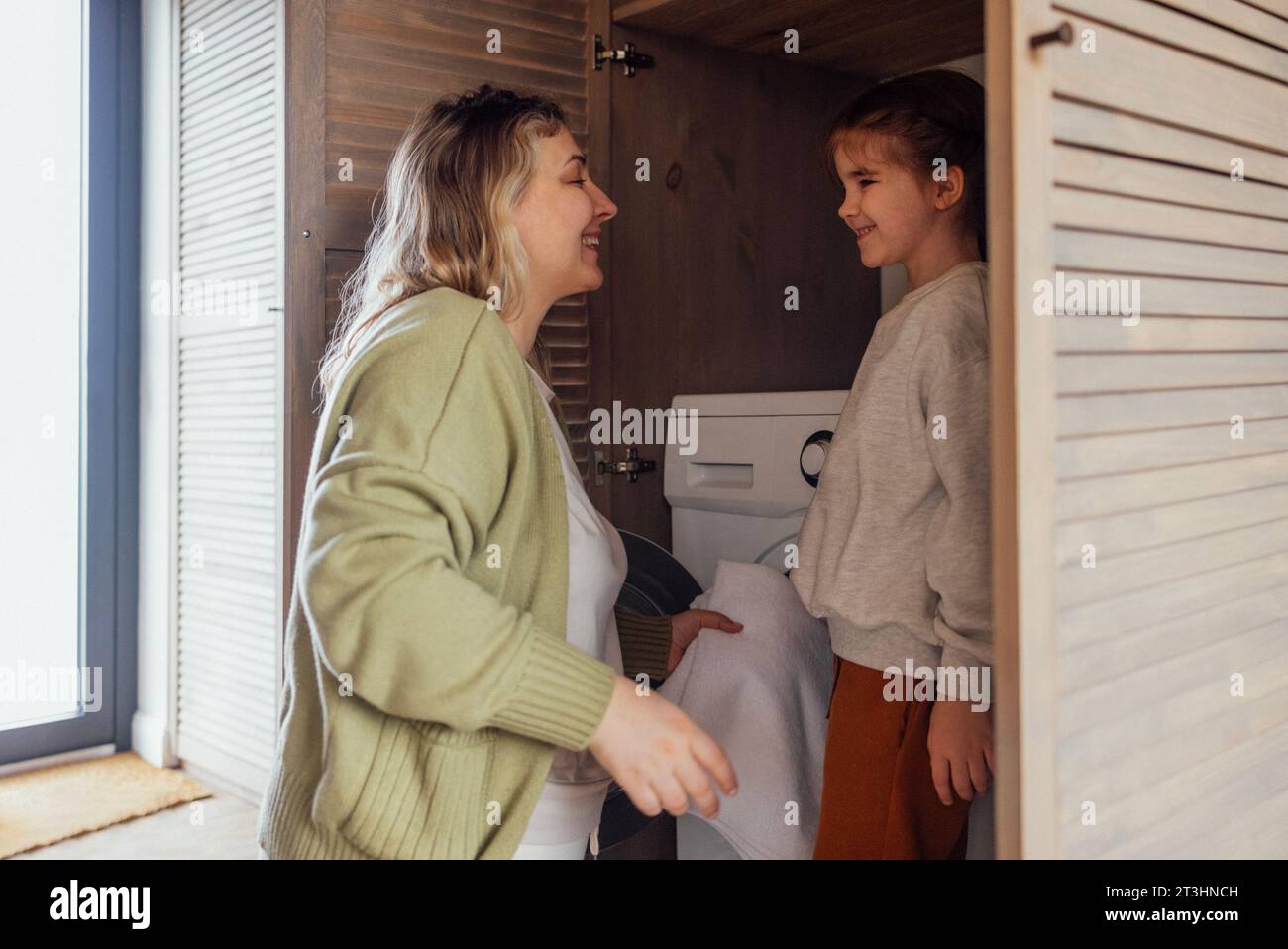 An attractive mom and her cute baby are doing household chores. A young ...