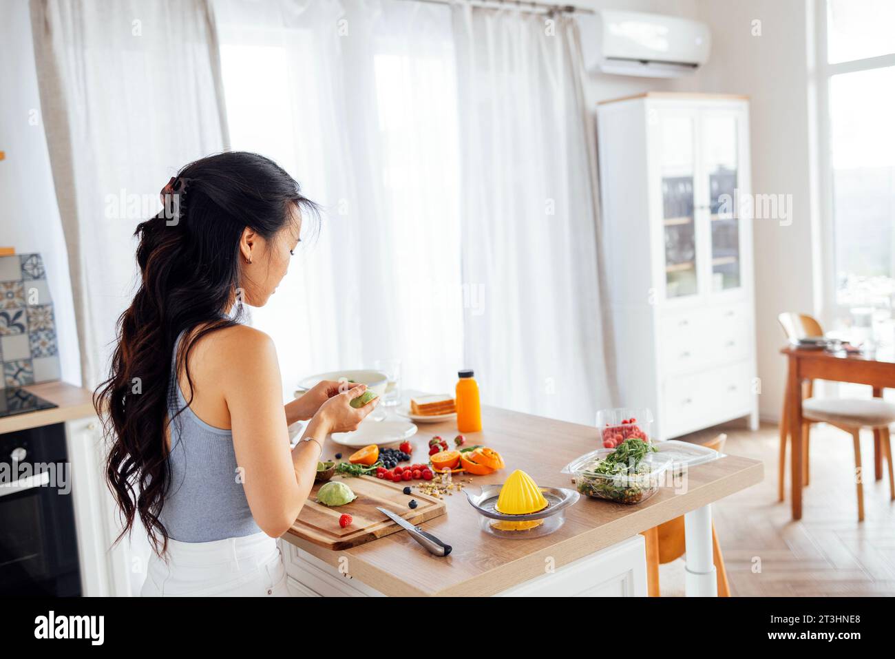 An attractive cute Asian woman smiles and cooks breakfast in the ...