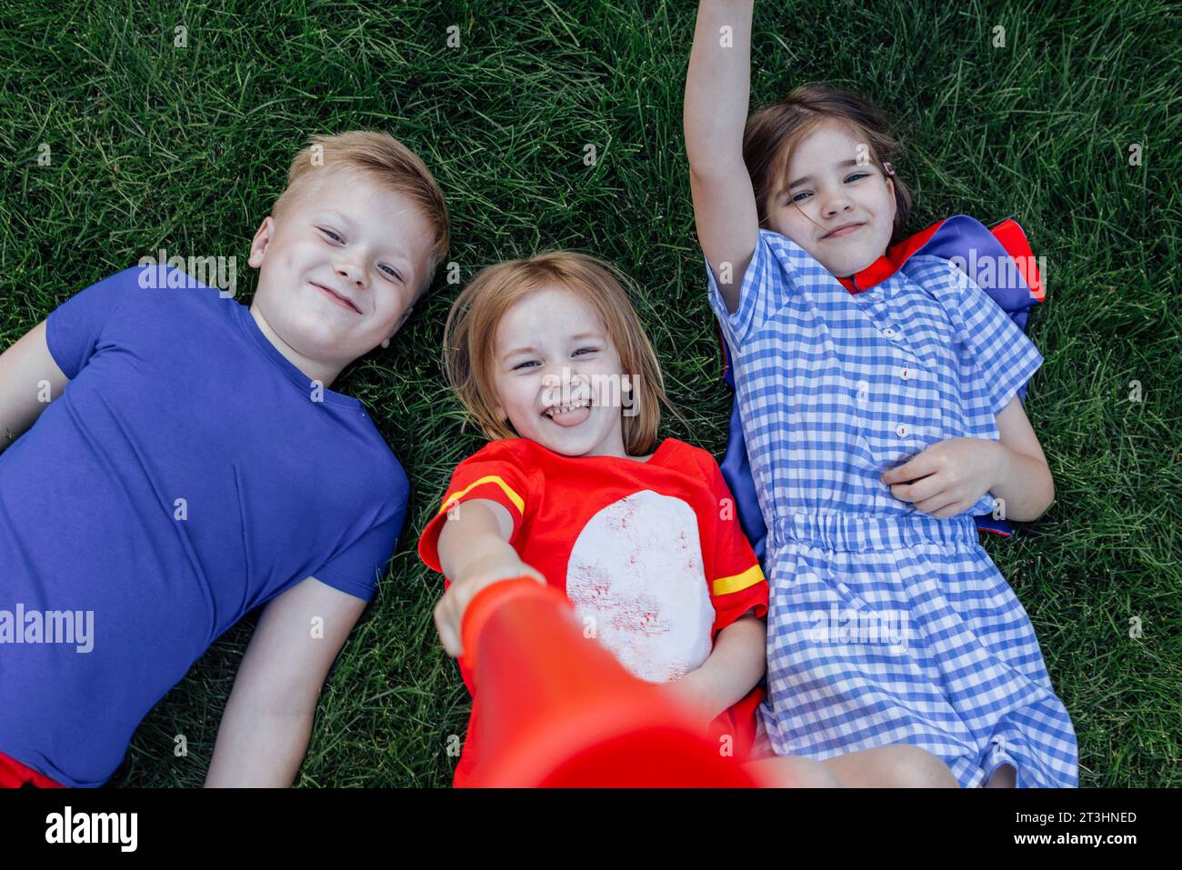 Children lie and laugh on the green lawn. Cute kids have fun outdoors ...