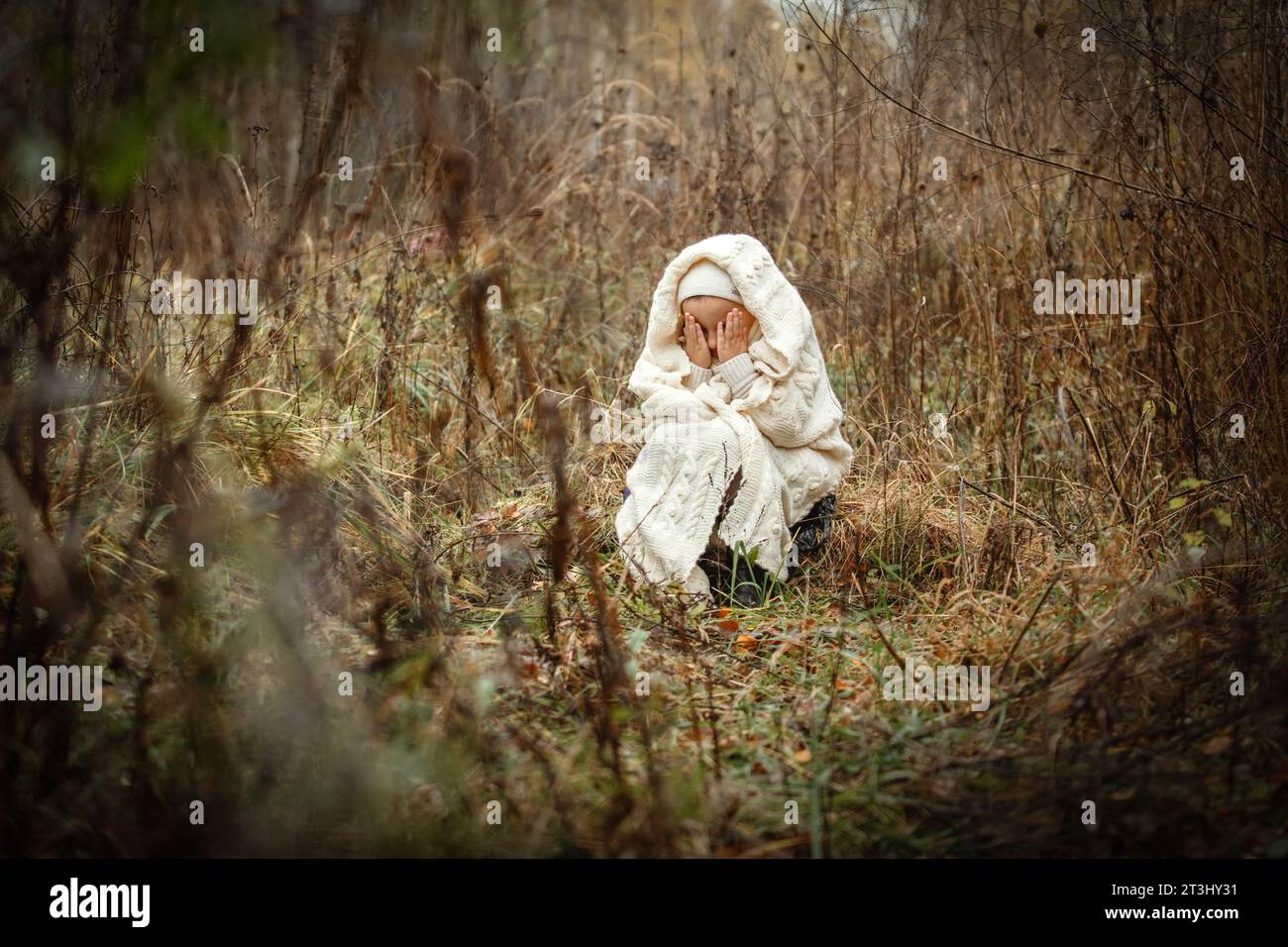 A girl sits alone in the autumn forest, she has closed her eyes - she ...