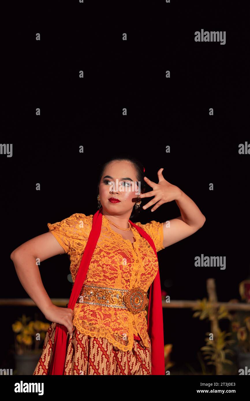 Balinese dancers in yellow color traditional costumes present the dance ...