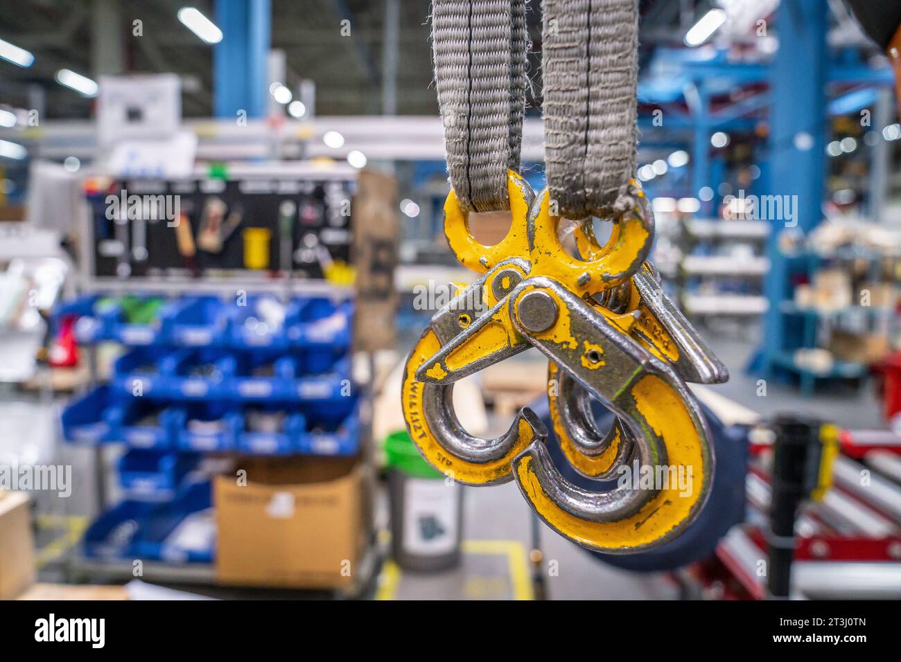 Two yellow metal load hooks against blurred factory warehouse ...