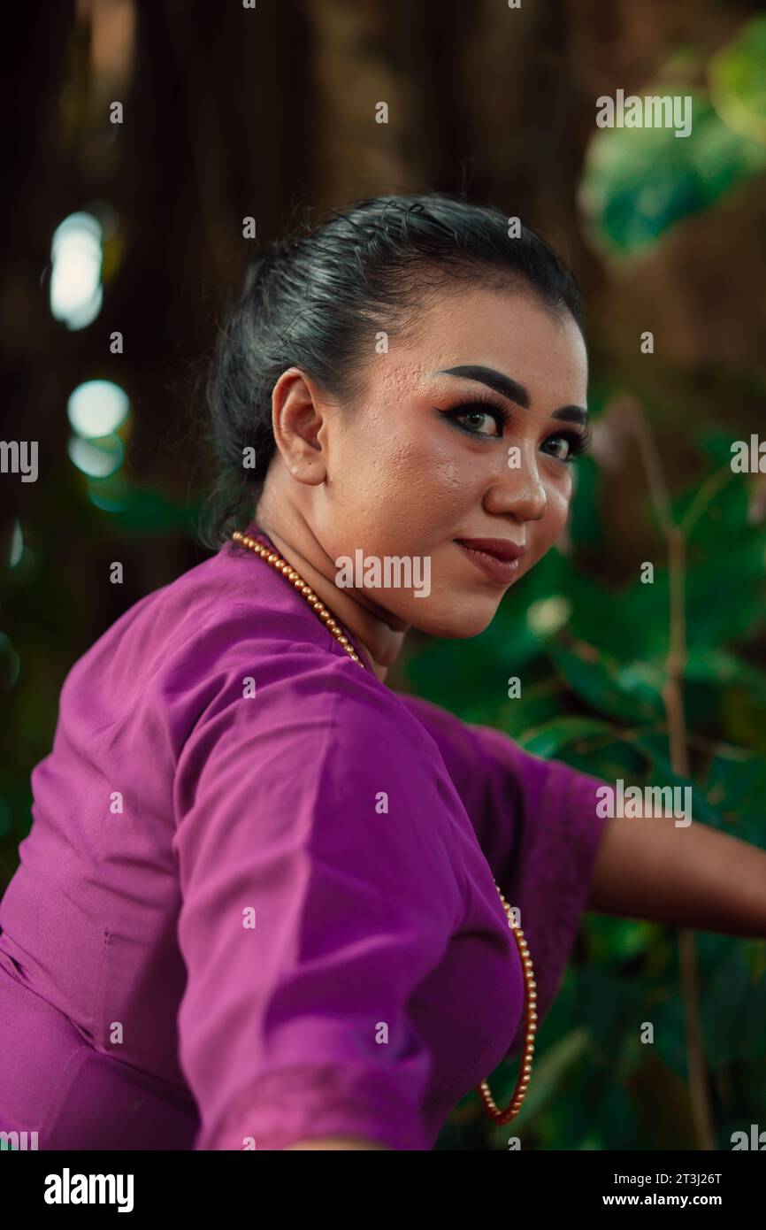 The face of a Javanese woman with makeup and a traditional purple dress ...
