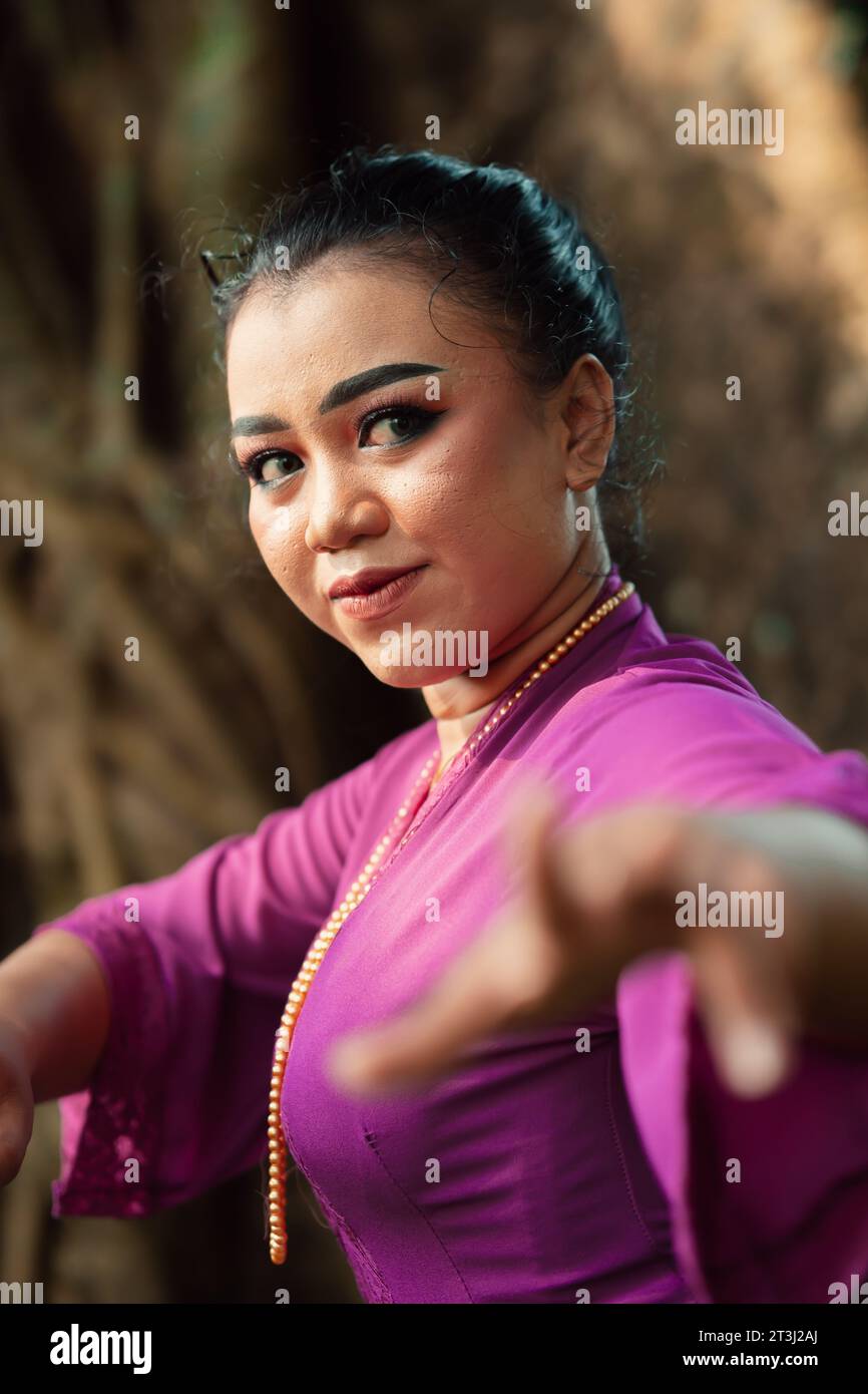 The face of a Javanese woman with makeup and a traditional purple dress ...