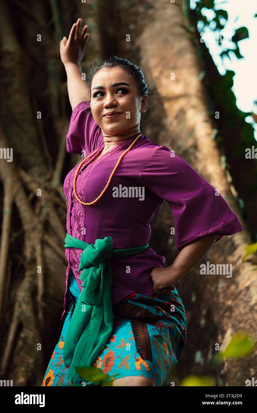 An Indonesian woman bravely poses while raising her hands in a purple ...