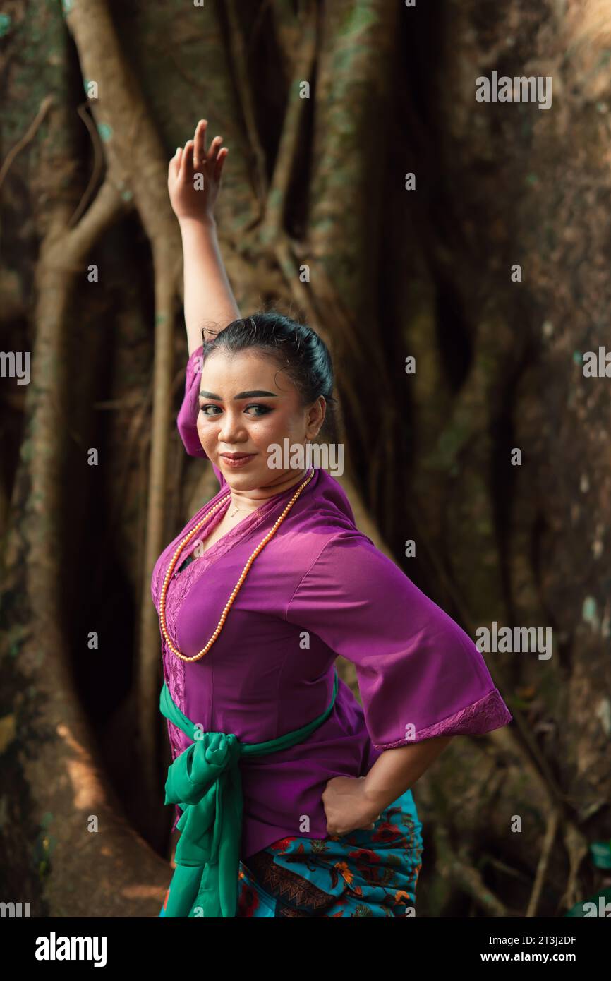 An Indonesian woman bravely poses while raising her hands in a purple ...