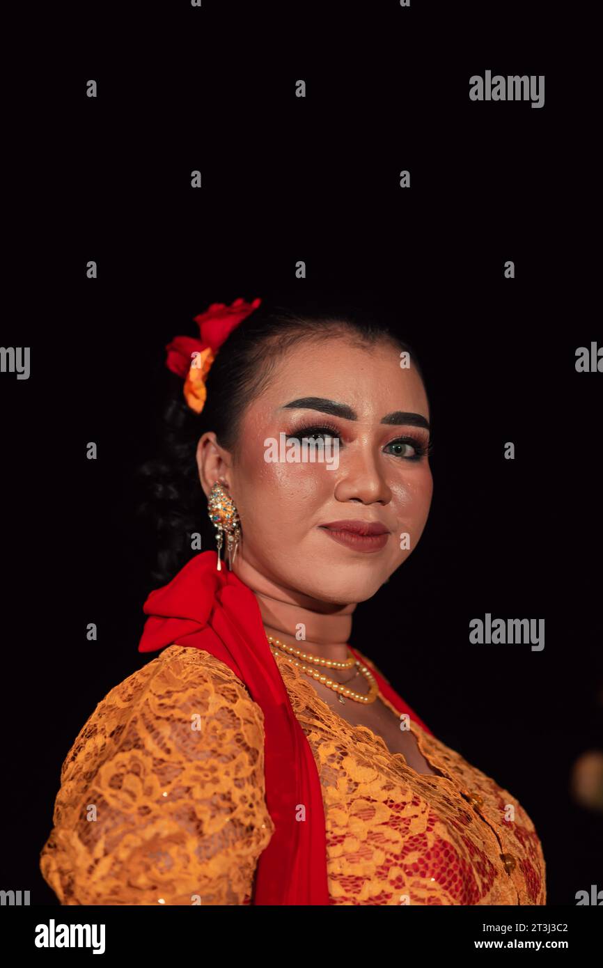 Javanese woman in a traditional orange dress while wearing makeup and a ...