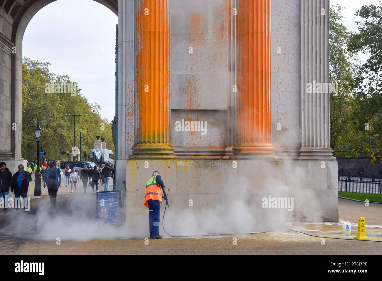 London, UK. 25th October 2023. A worker cleans the orange paint sprayed ...