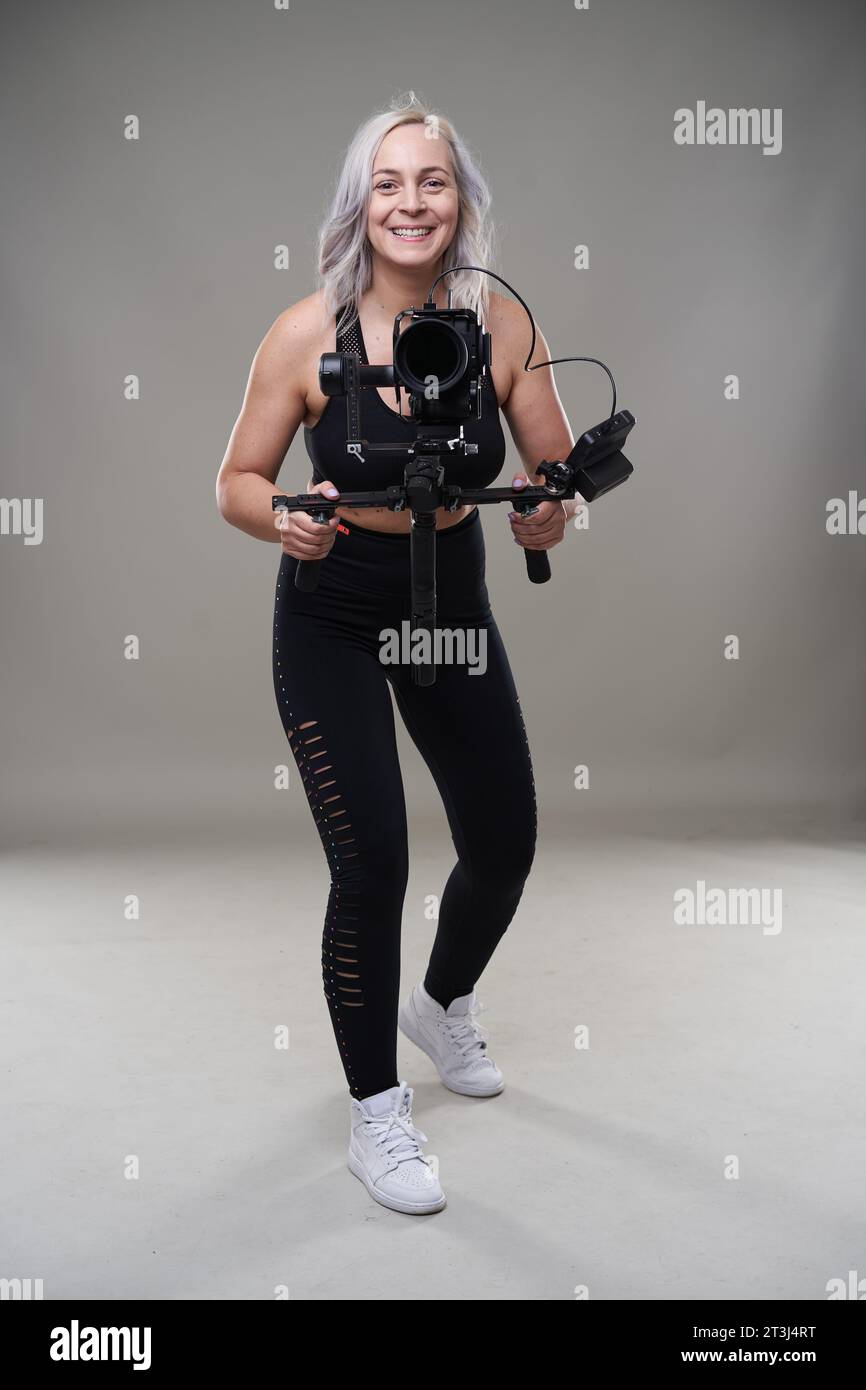 Woman videographer with cinema camera on gimbal isolated on gray ...