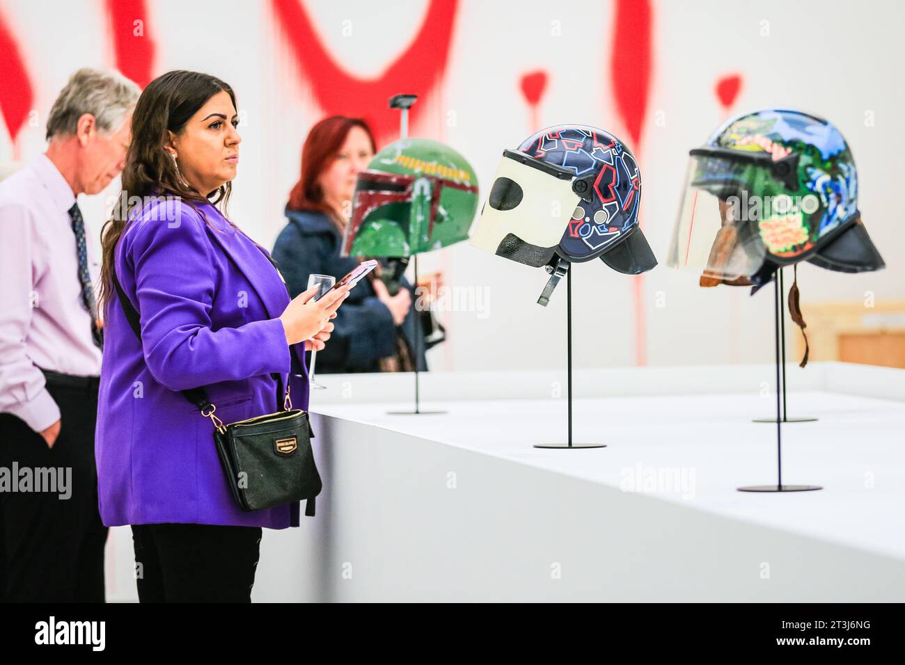 London, UK. 25th Oct, 2023. Visitors look at the helmets. 'R.I.O.T ...