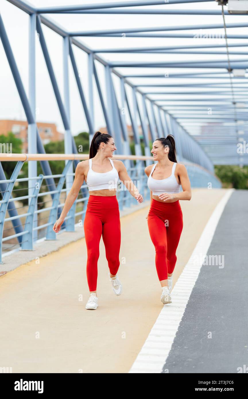 Two female athletes running smiling Stock Photo - Alamy