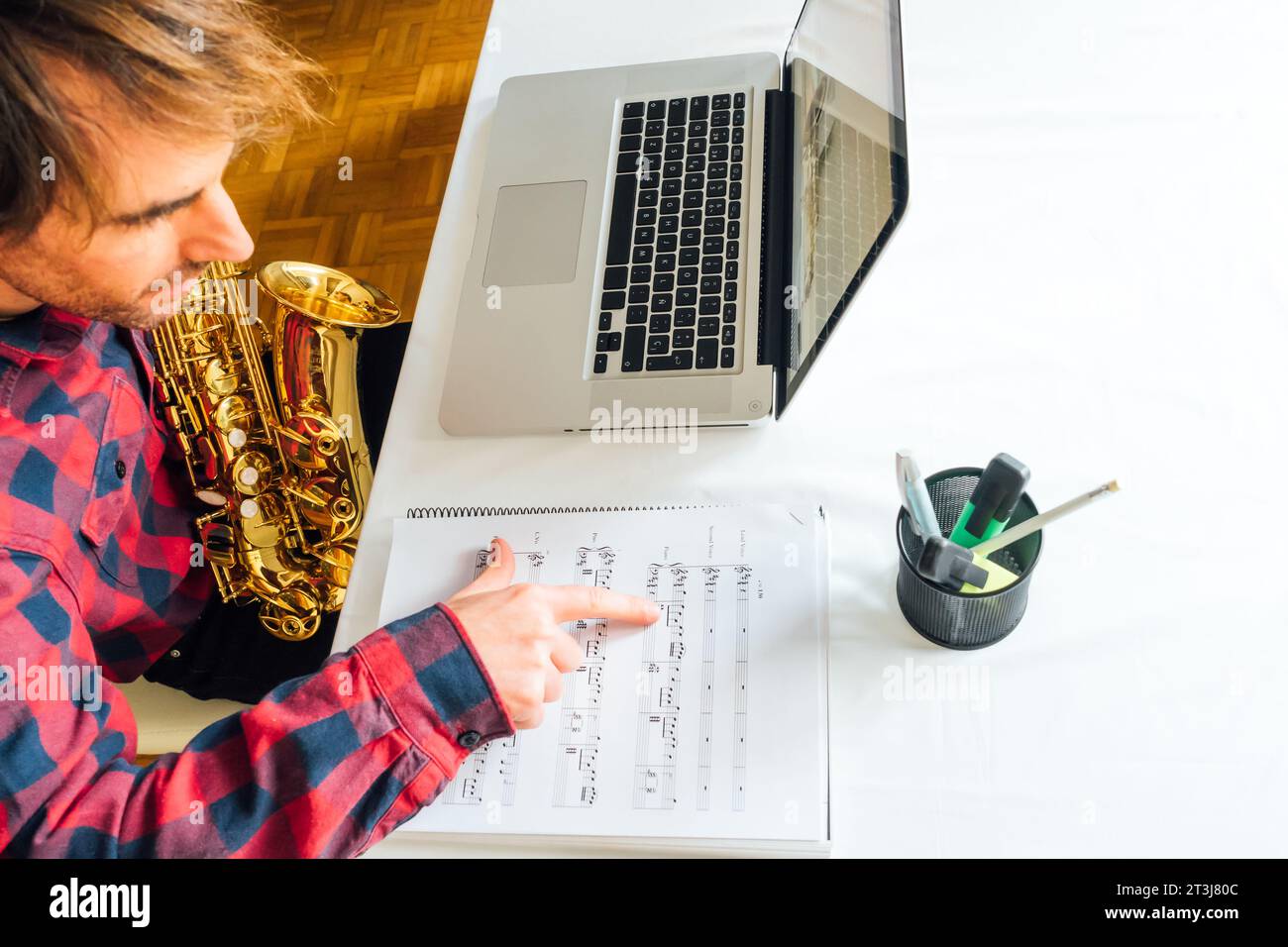 man pointing over notes on sheet music during his saxophone online ...
