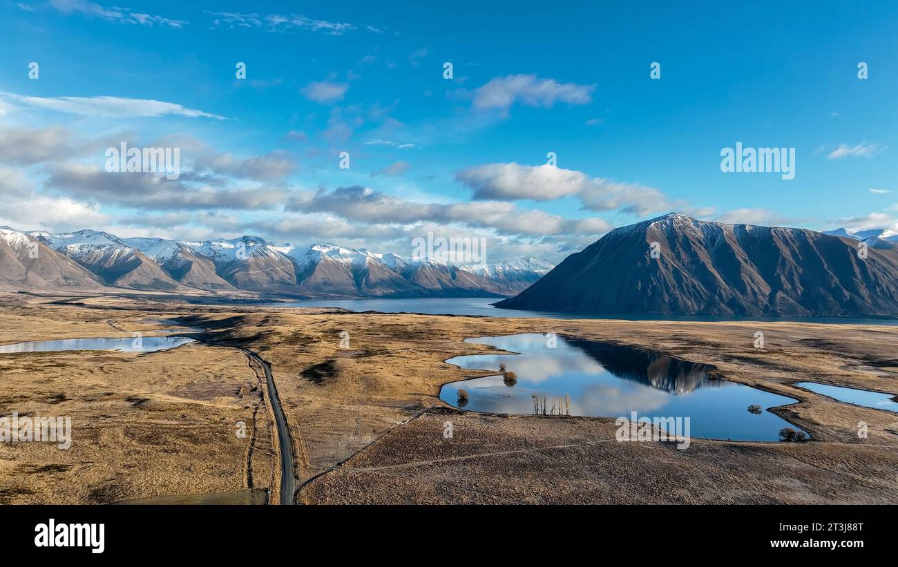 Remote country road winding through several lakes and alpine tussock ...
