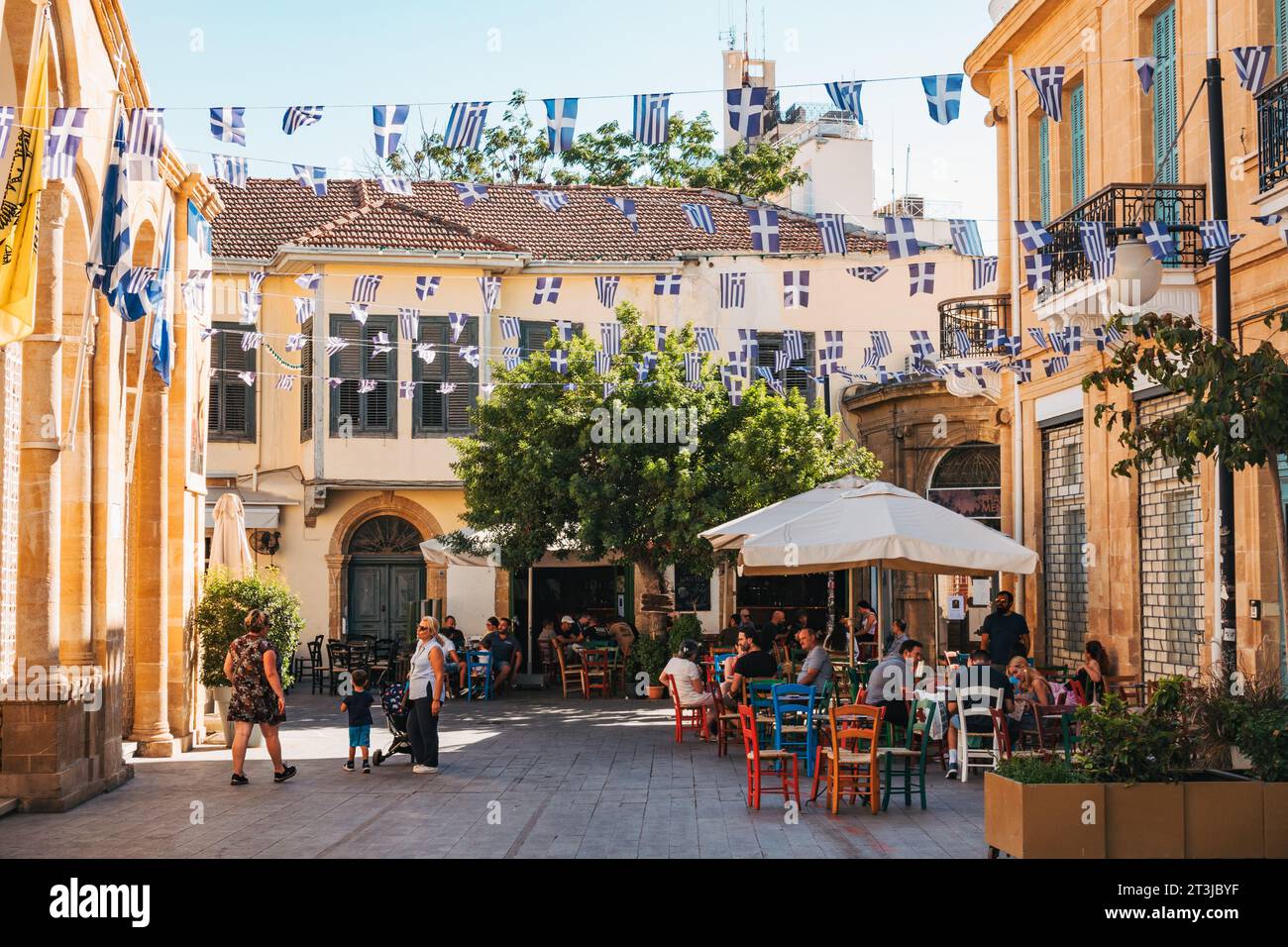 Greek flags fly above restaurant patrons dining outdoors in the old ...