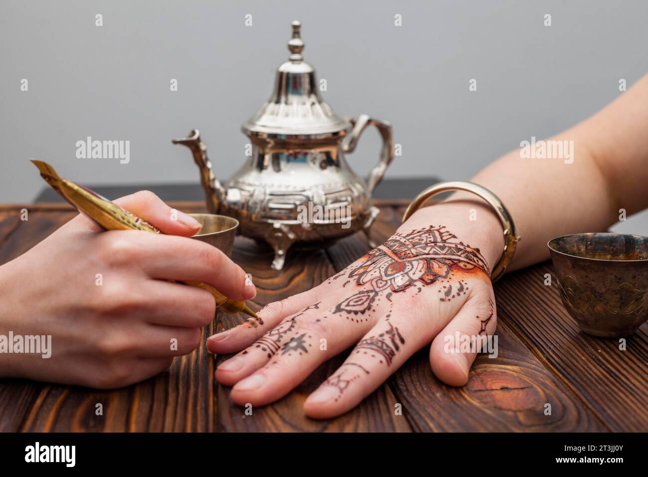 Artist making mehndi womans hand near teapot Stock Photo - Alamy