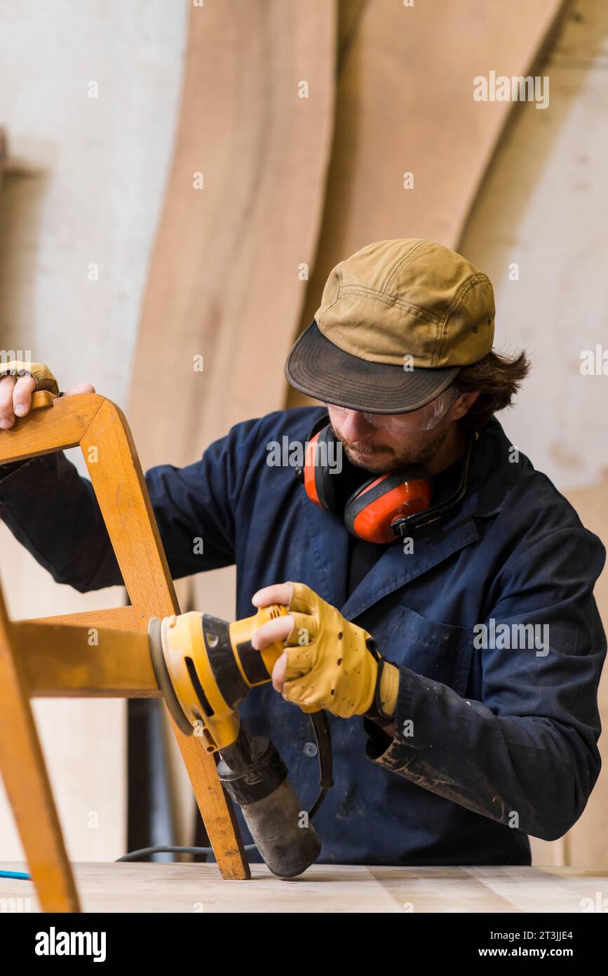 Close up male carpenter sanding furniture with power tool workbench ...