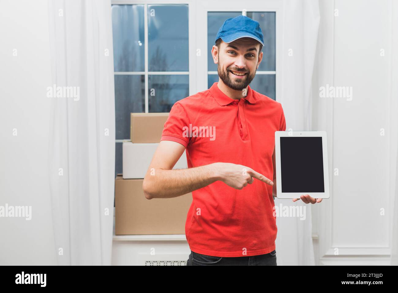 Delivery man pointing tablet Stock Photo - Alamy