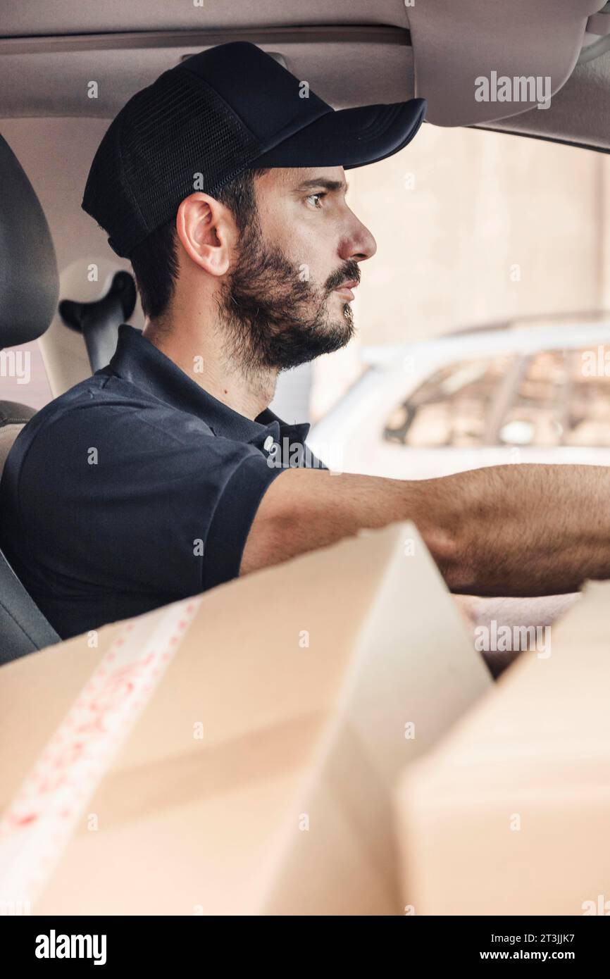 Delivery man with cardboard boxes driving vehicle Stock Photo - Alamy
