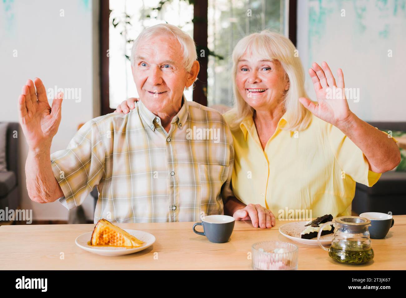 Friendly elderly couple waving with hands Stock Photo - Alamy