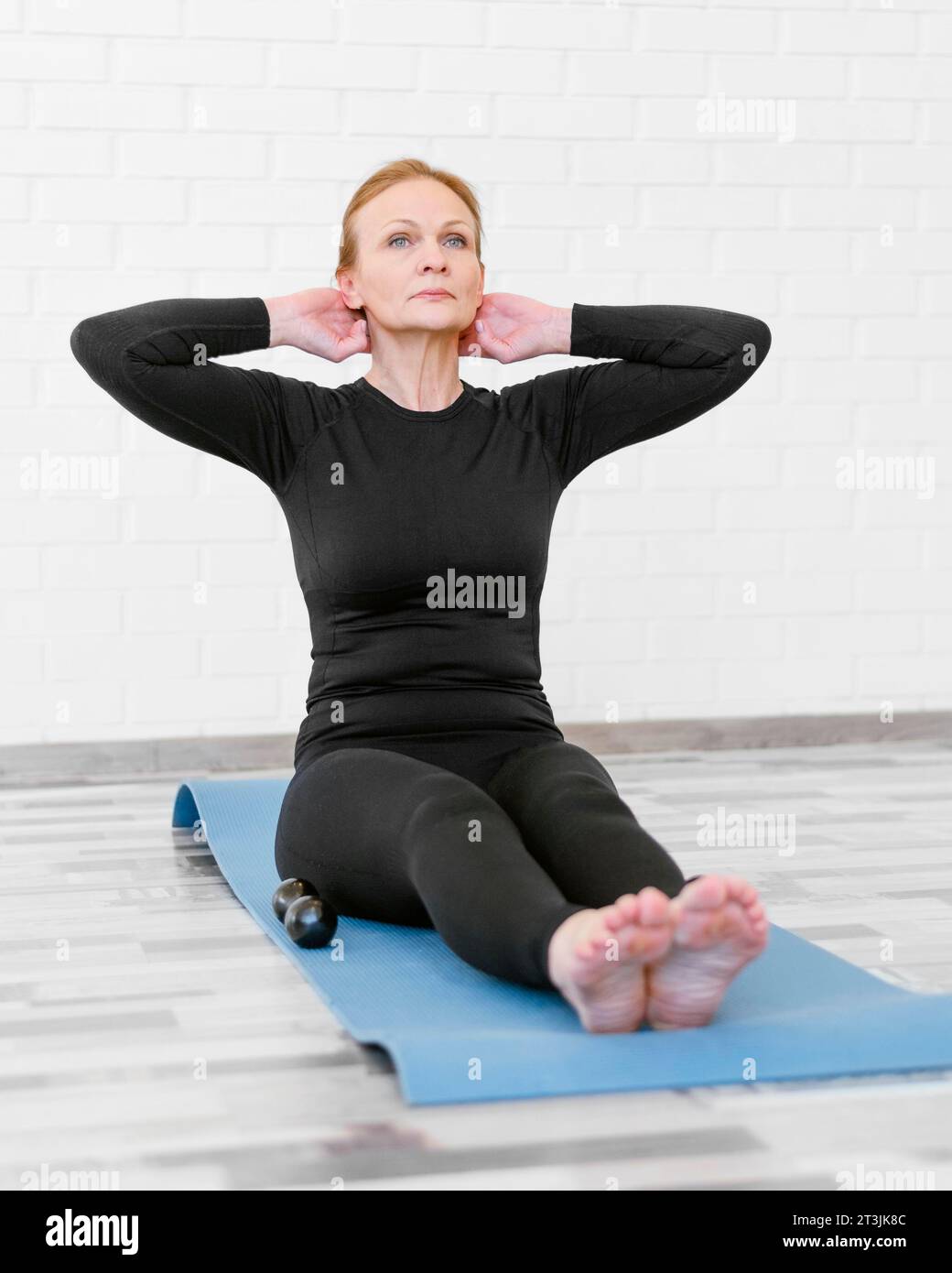 Full shot woman sitting mat Stock Photo - Alamy