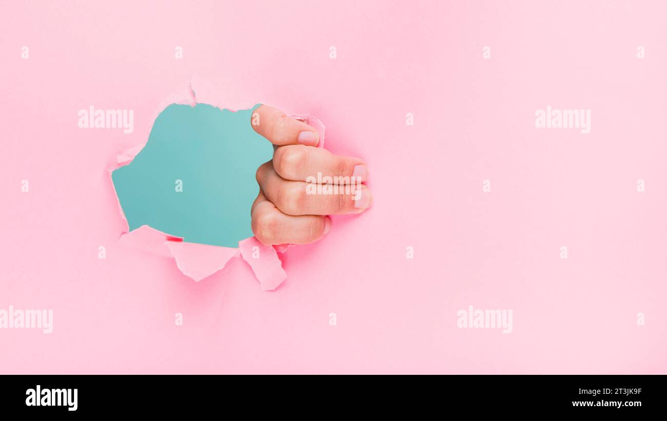 Hand through paper hole Stock Photo - Alamy