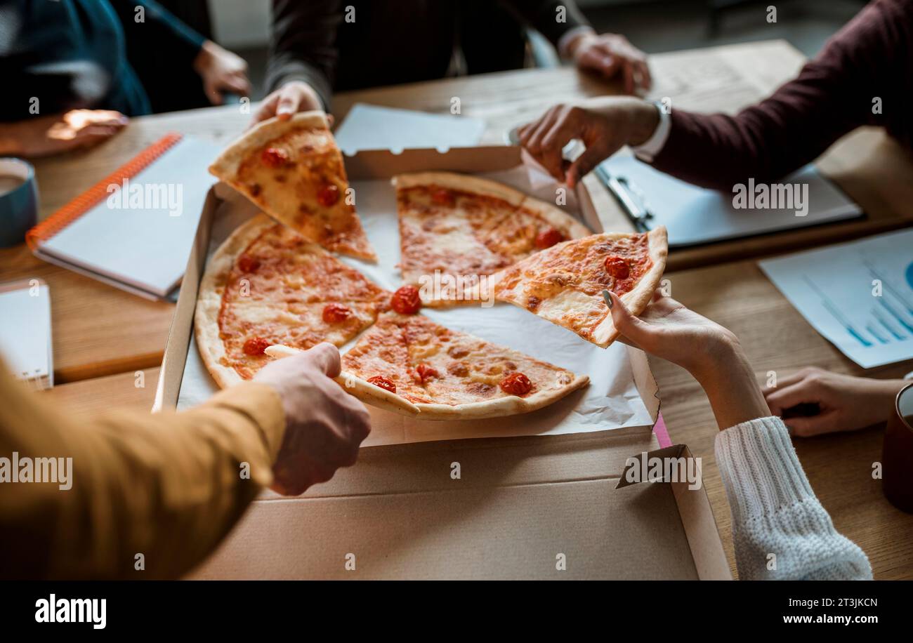 High angle colleagues having pizza during office meeting break Stock ...