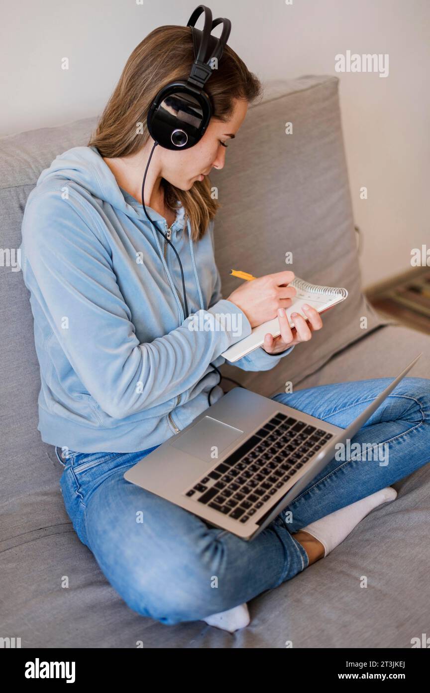 High angle woman couch taking notes from online class Stock Photo - Alamy