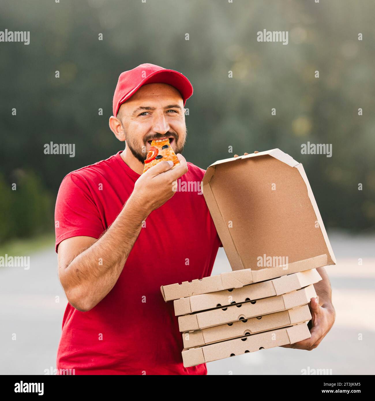 Medium shot delivery guy eating pizza Stock Photo - Alamy