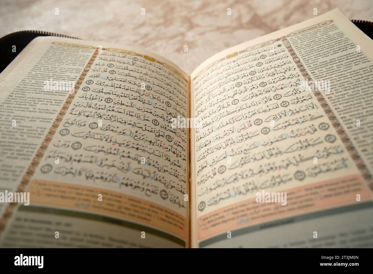 Man's hand flips open page of Quran on black background. The Quran is ...