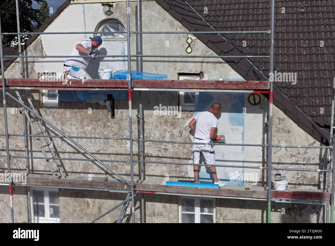 Painters on scaffolding plastering the facade of a house from 1830, old ...