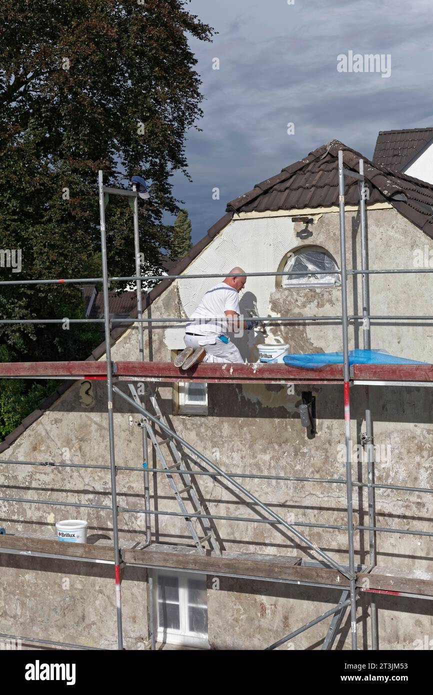 Painter on scaffolding plastering the facade of a house from 1830, old ...