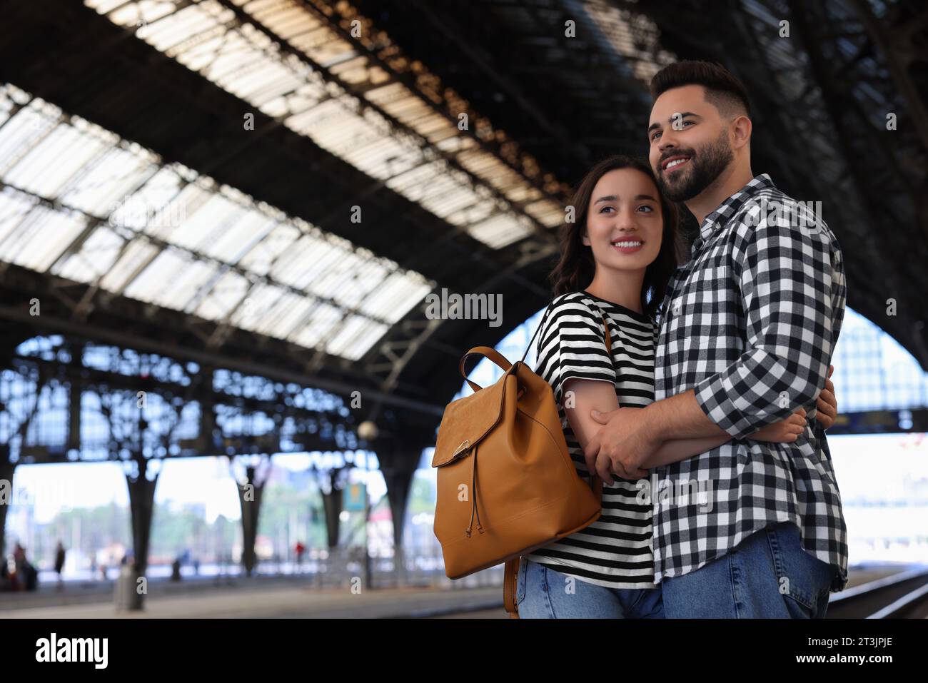 Long-distance relationship. Beautiful couple on platform of railway station, space for text ...