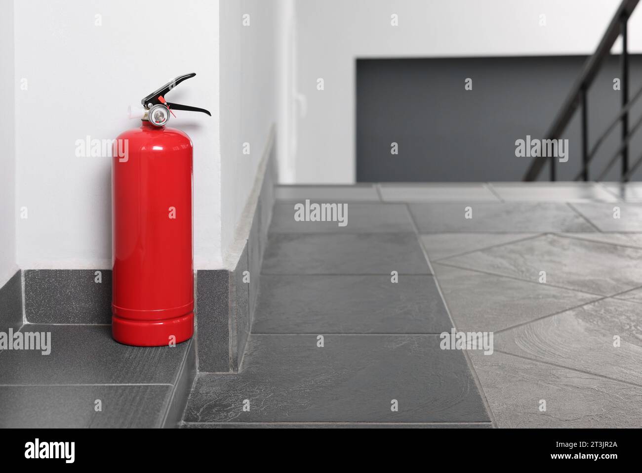 Red fire extinguisher near white wall, space for text Stock Photo - Alamy