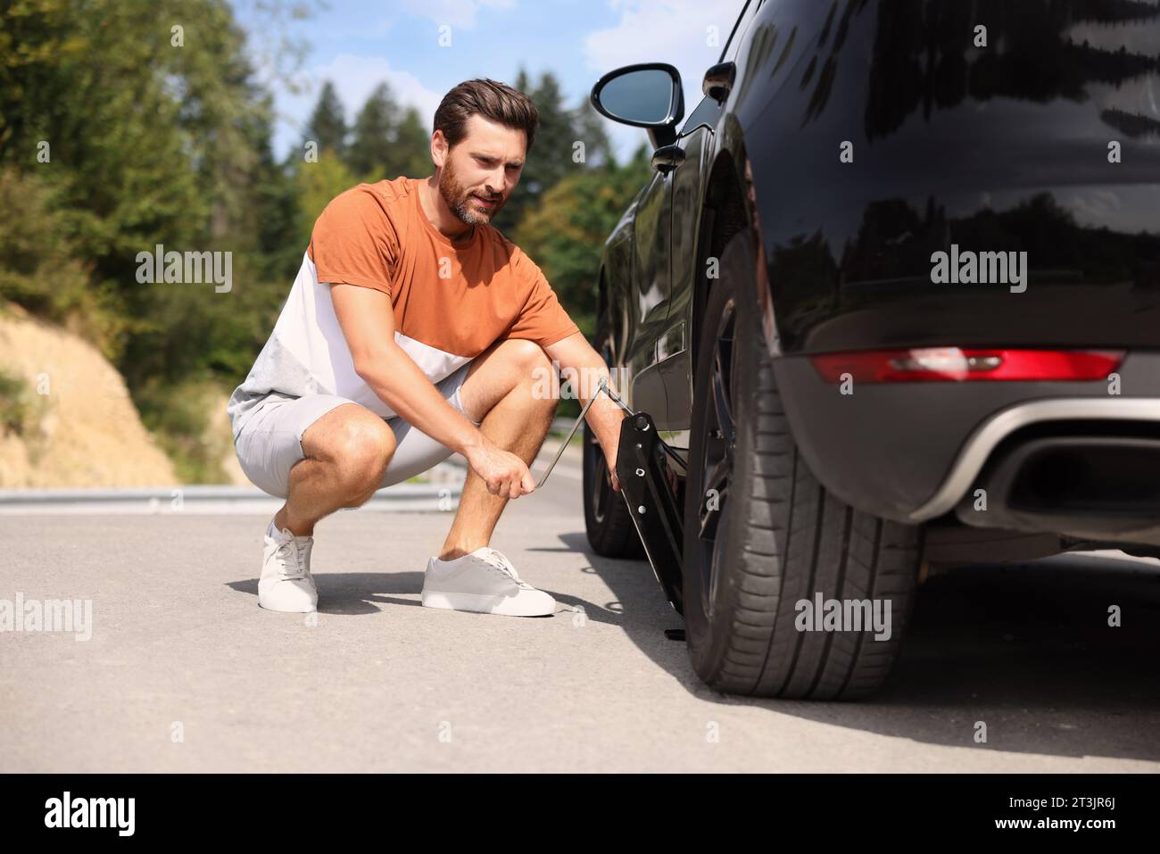Man lifting car to change wheel on roadside outdoors Stock Photo - Alamy
