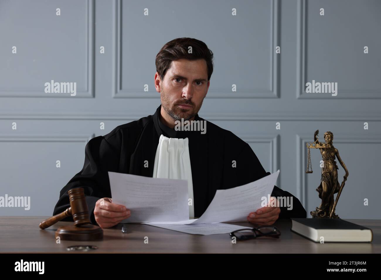 Judge with gavel and papers sitting at wooden table indoors Stock Photo ...