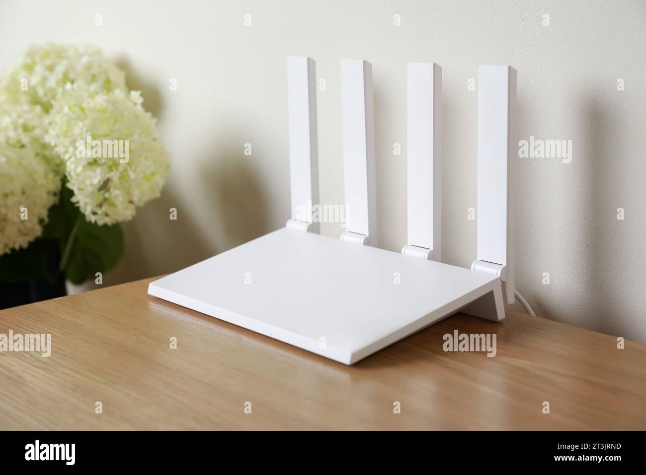 New modern Wi-Fi router on wooden table near white wall Stock Photo - Alamy