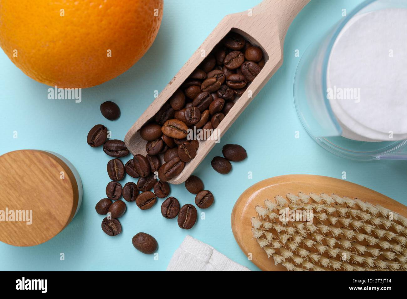 Coffee beans, orange and brush on light blue background, flat lay. Anti ...