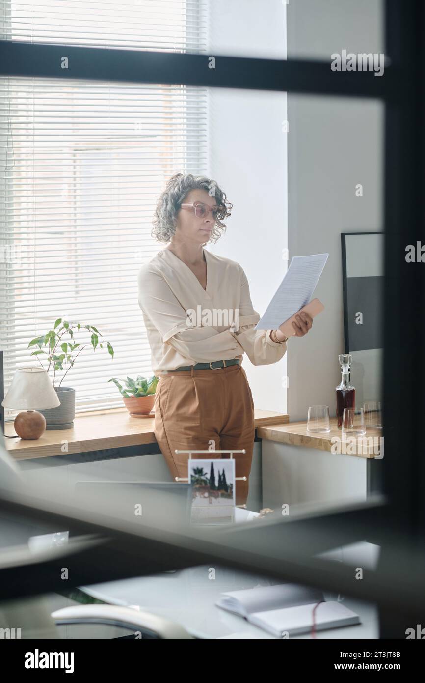 Experienced female chief executive officer looking through financial ...