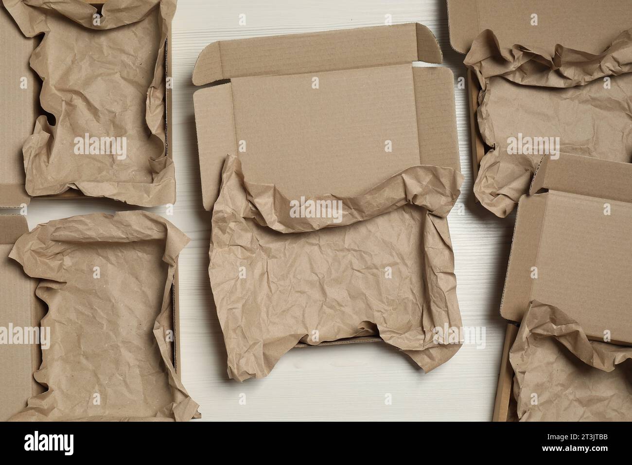 Many open cardboard boxes with crumpled paper on white wooden floor ...