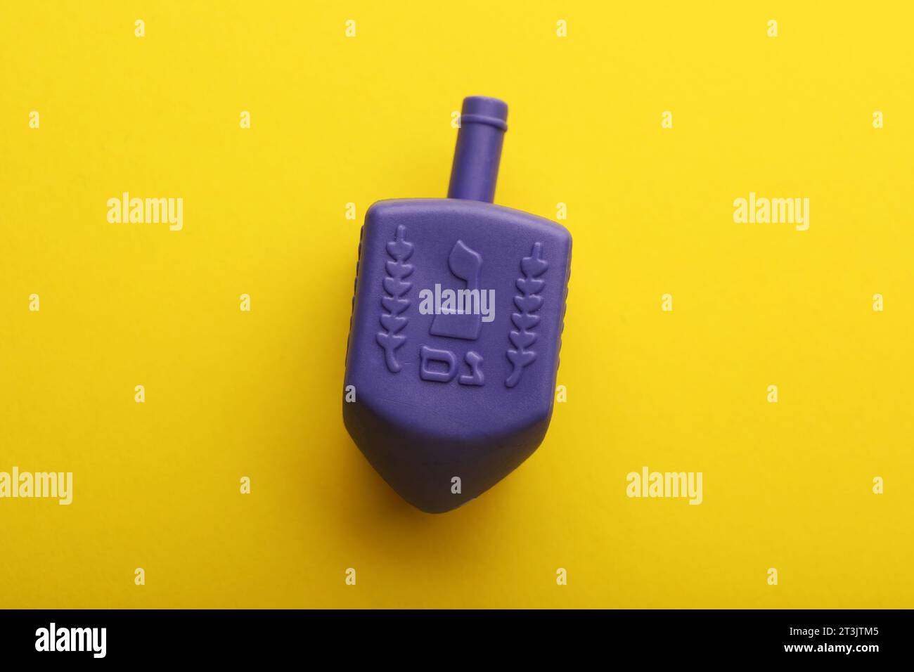 Purple dreidel on yellow background, top view. Traditional Hanukkah ...