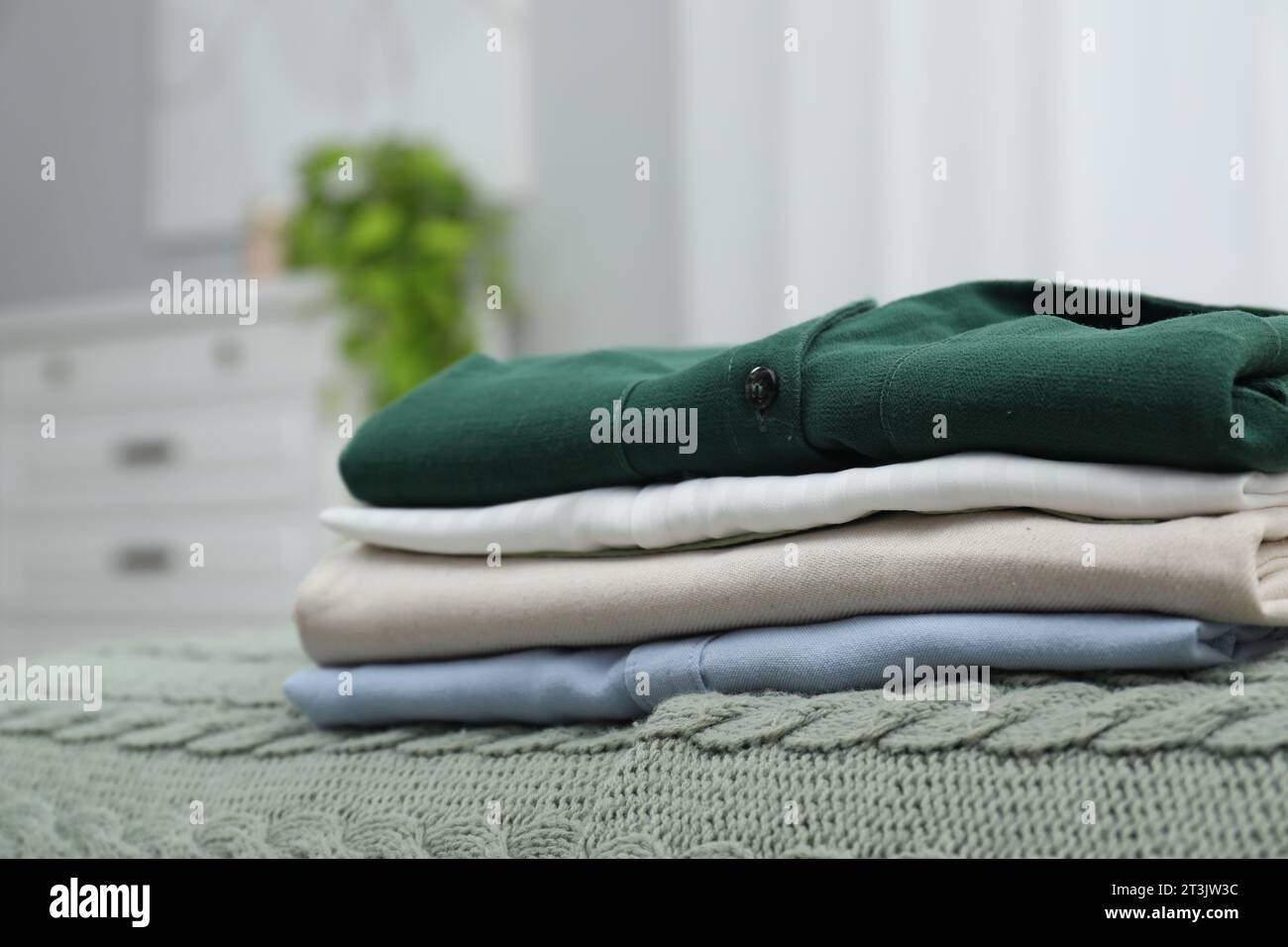 Sorting and organizing. Stack of different folded clothes on bed ...