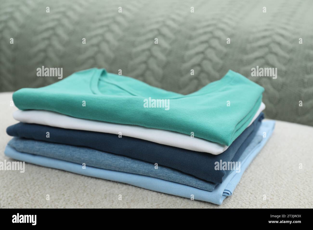 Sorting and organizing. Stack of different folded clothes on ottoman ...
