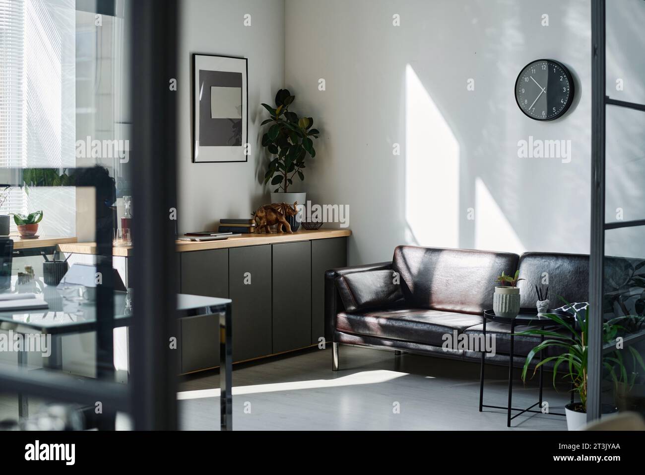 Part of spacious office with black leather couch standing in the corner ...