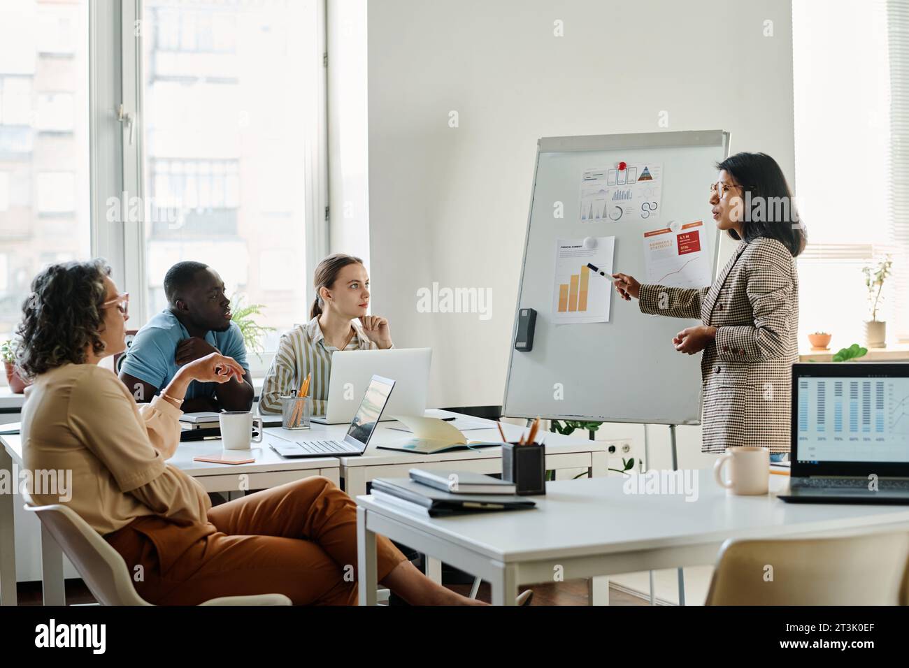 Young confident female analyst pointing at paper document with ...